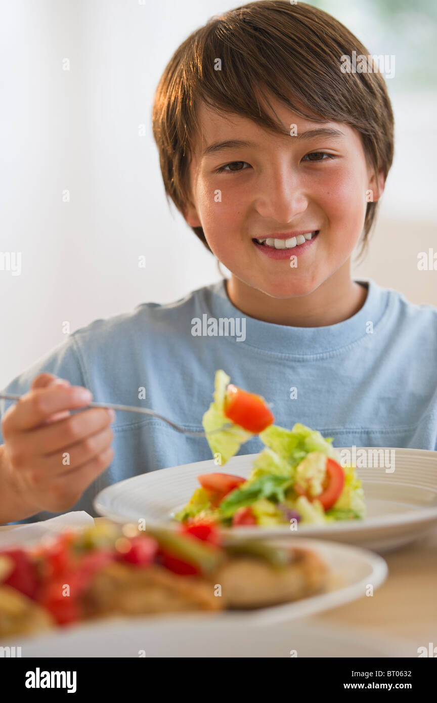 Smiling mixed race boy eating salad Stock Photo - Alamy