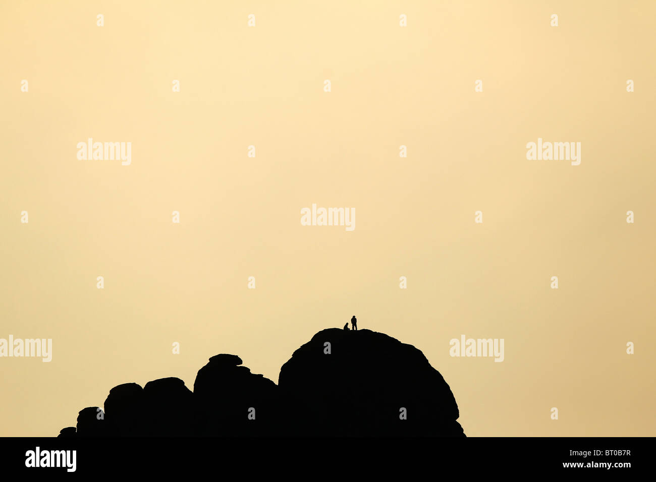 A silhouette two people standing on top of Haytor at sunset on Dartmoor ...