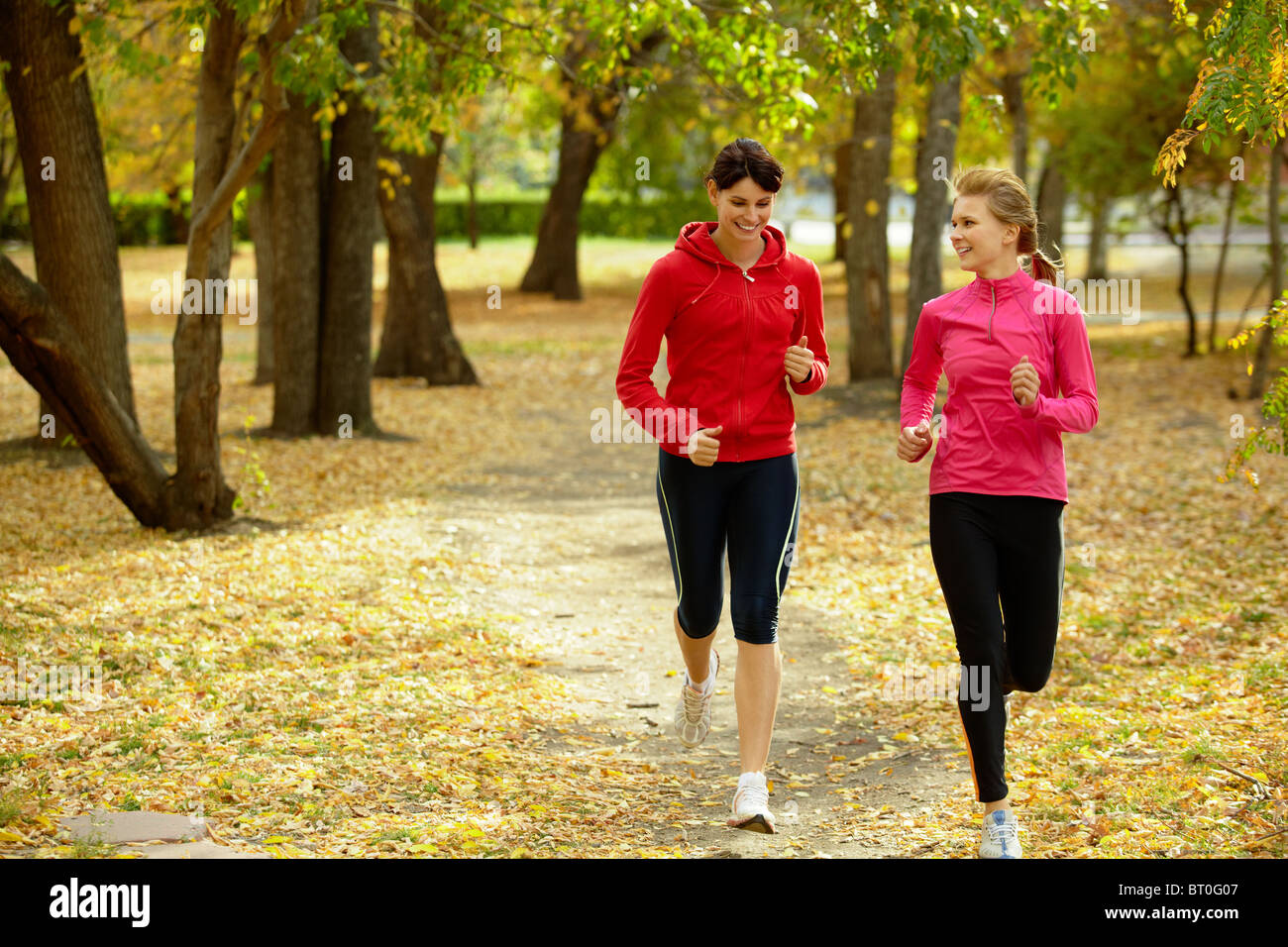 Two girls racing in autumn park Stock Photo - Alamy