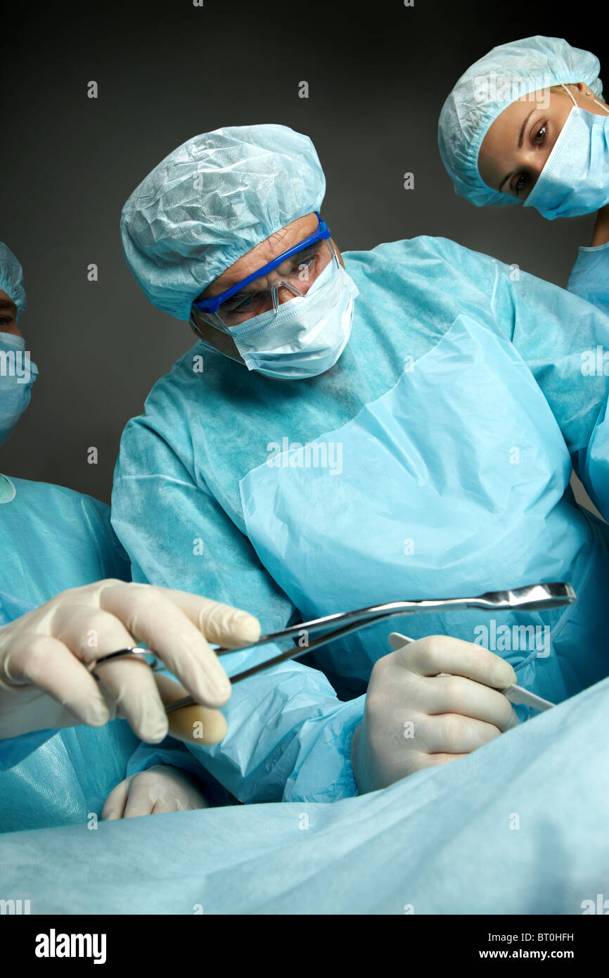 Side view of three surgeons operating Stock Photo - Alamy