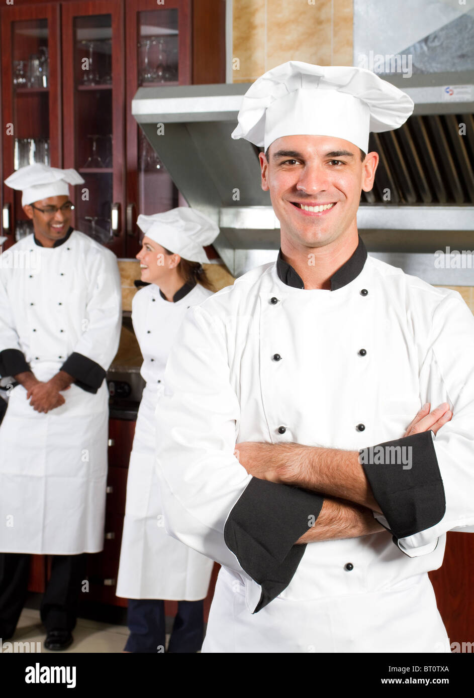 happy male professional chefs in industrial kitchen with colleagues ...