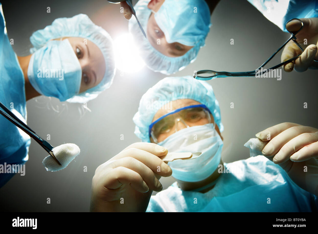 Three surgeons bending over a patient Stock Photo - Alamy