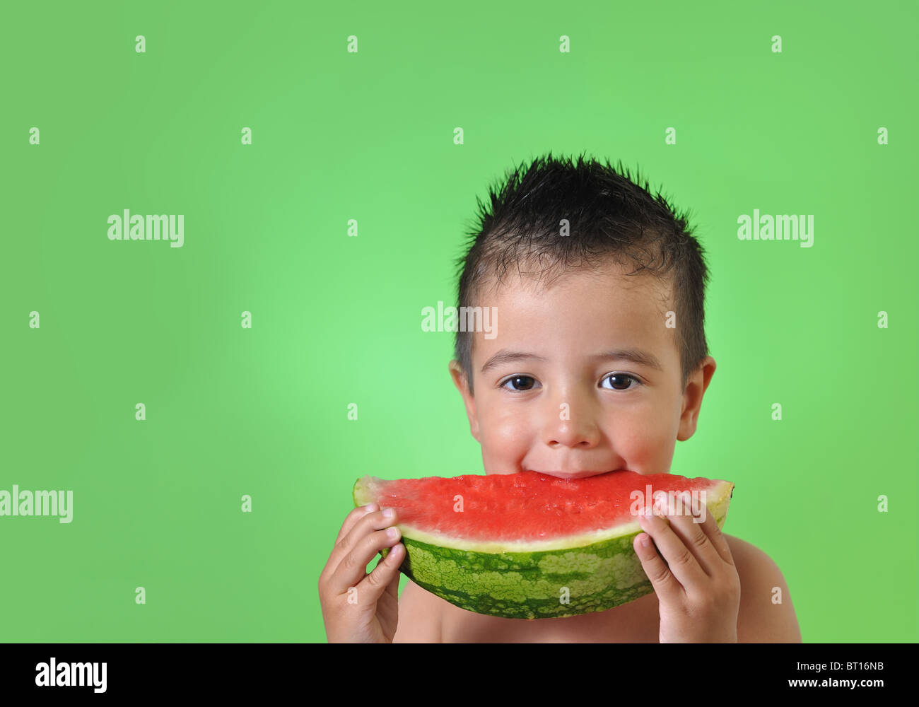 cute little kid eating a watermelon on a green background with copy ...