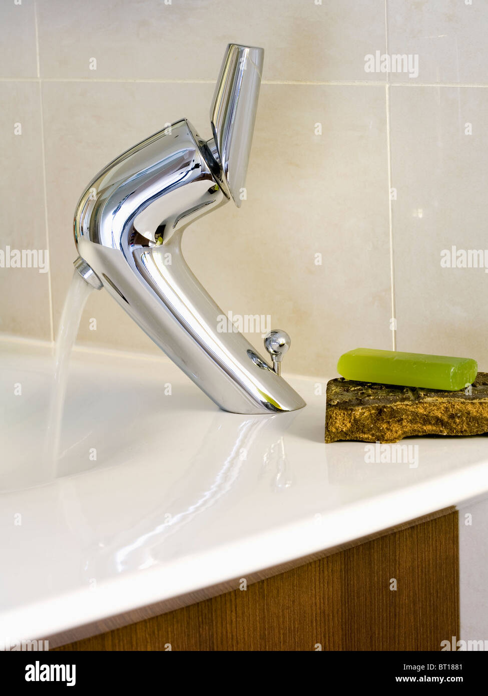 Close-up of modern stainless-steel mixer tap pouring water into basin ...