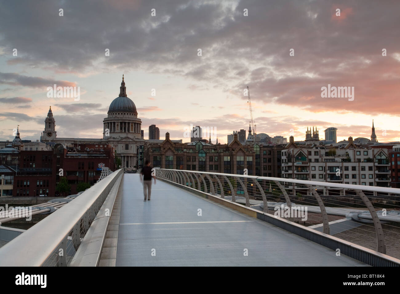 Man Walking over the Millenium Bridge over the River Thames at dawn ...