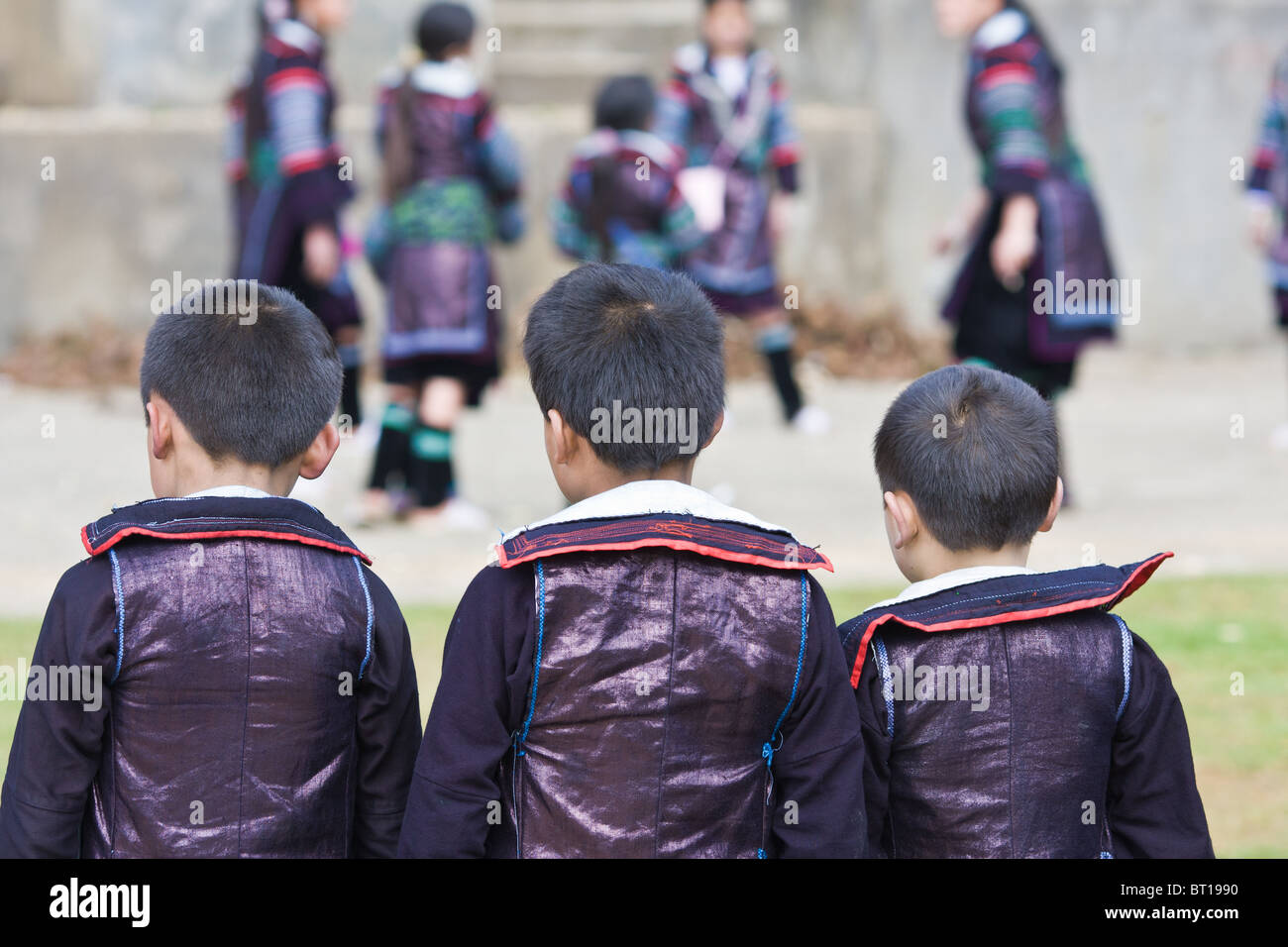 Three Black Hmong boys watch Black Hmong girls playing during Tet Stock ...