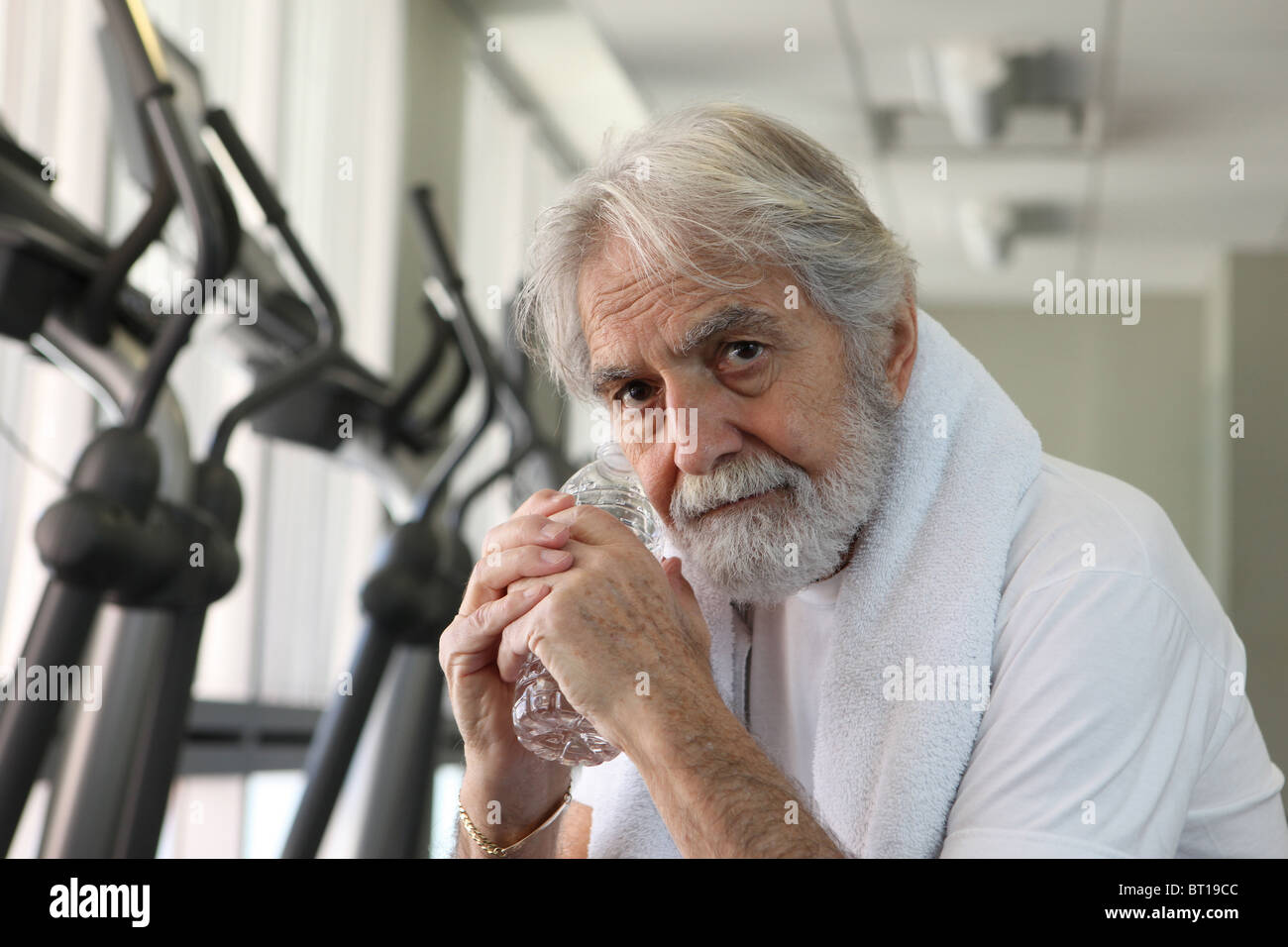 Physically fit and health conscious senior man in gym resting between ...