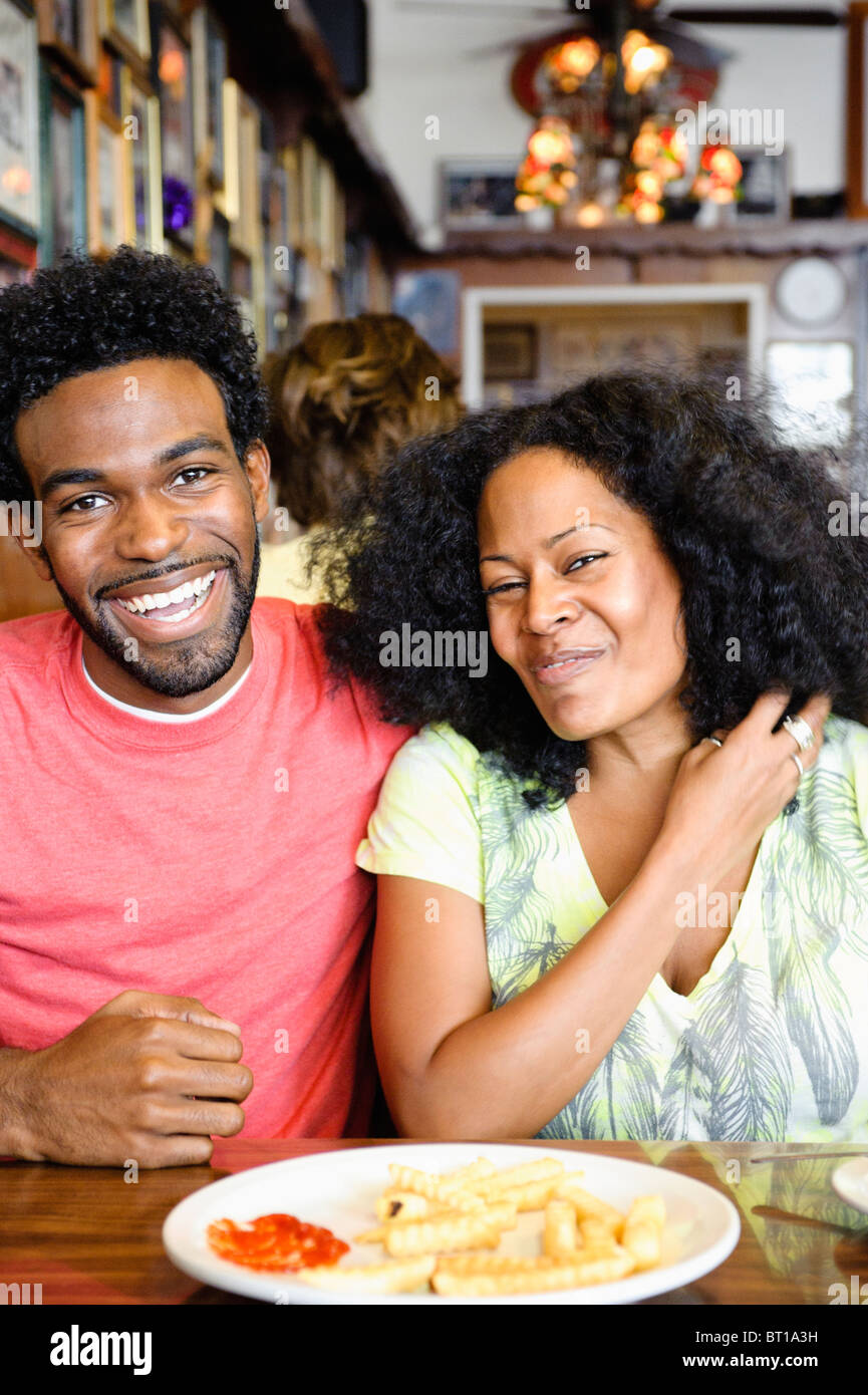 Smiling couple eating french fries in diner Stock Photo - Alamy