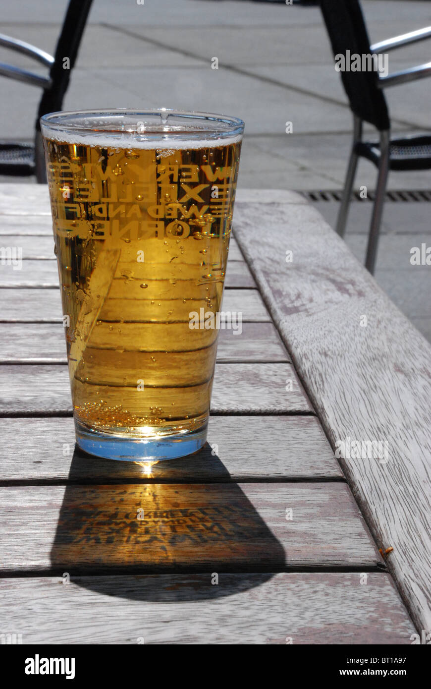 Pint of Beer / larger awaiting drinking on wooden table in sunshine ...