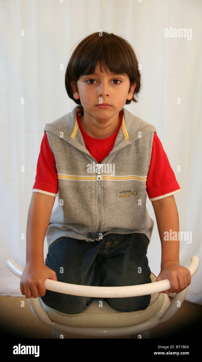 Portrait of serious brunette boy in chair Stock Photo - Alamy