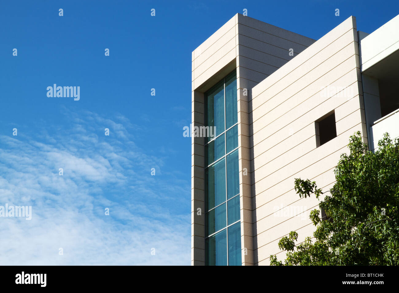 Corner of a building and elevator tower enclosed by green glass with ...