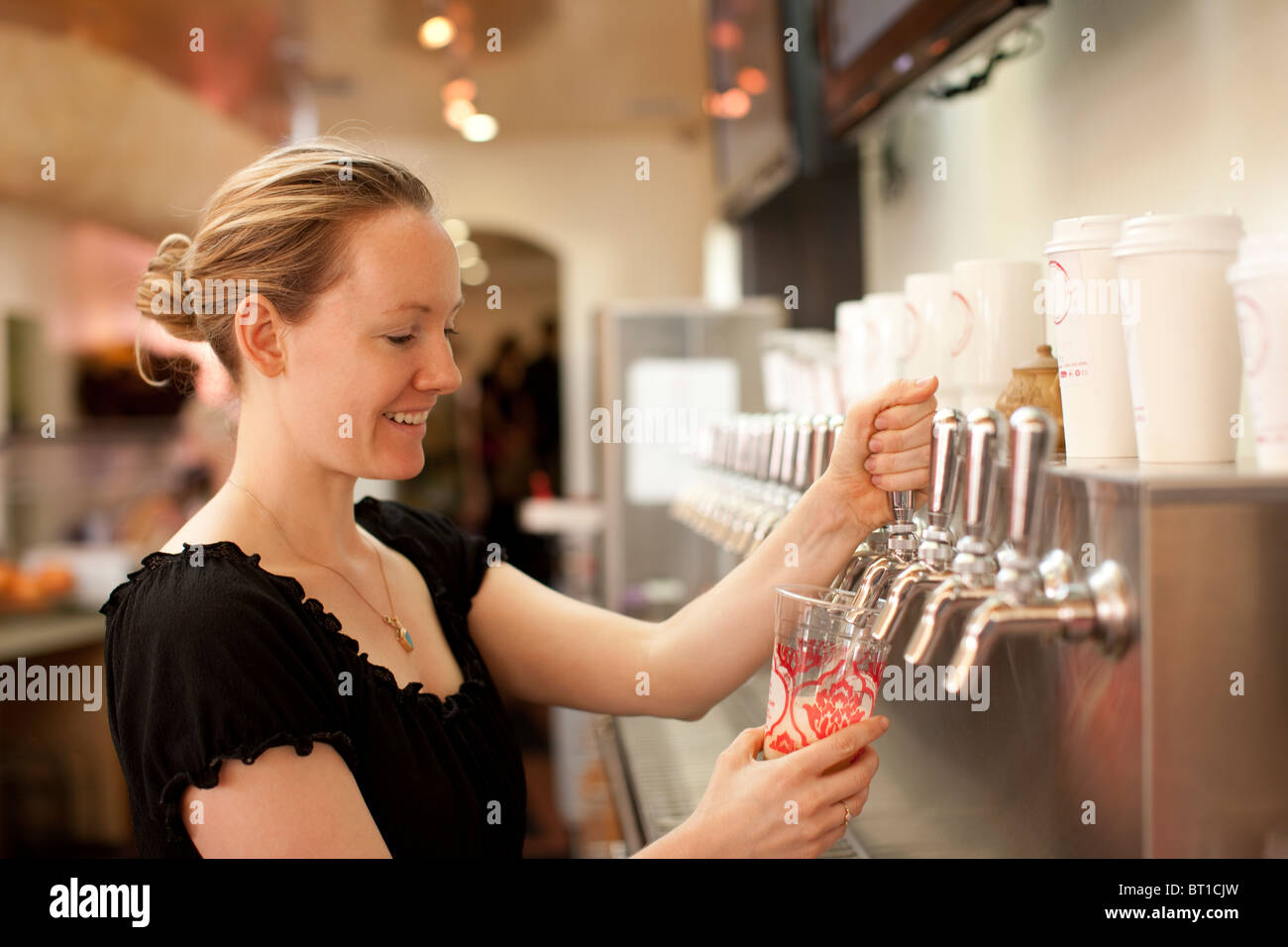 Smiling Caucasian woman filling cup from dispenser Stock Photo - Alamy