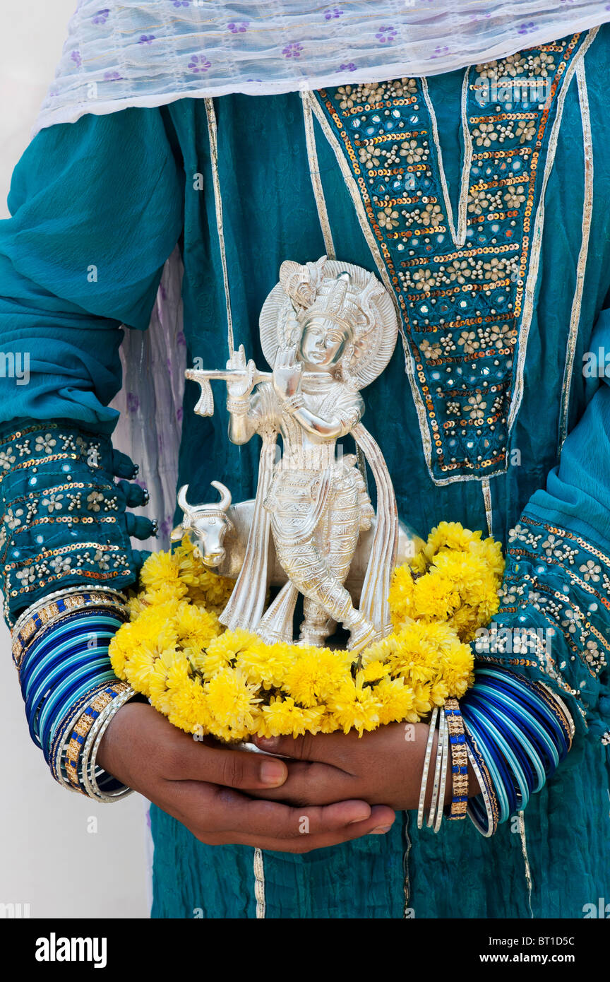 Indian girl holding a Silver Krishna statue Stock Photo - Alamy