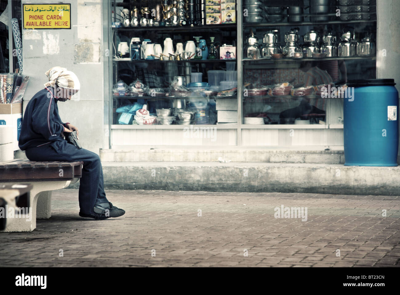 Editorial photo of the woman sitting on the bench near the shop and ...