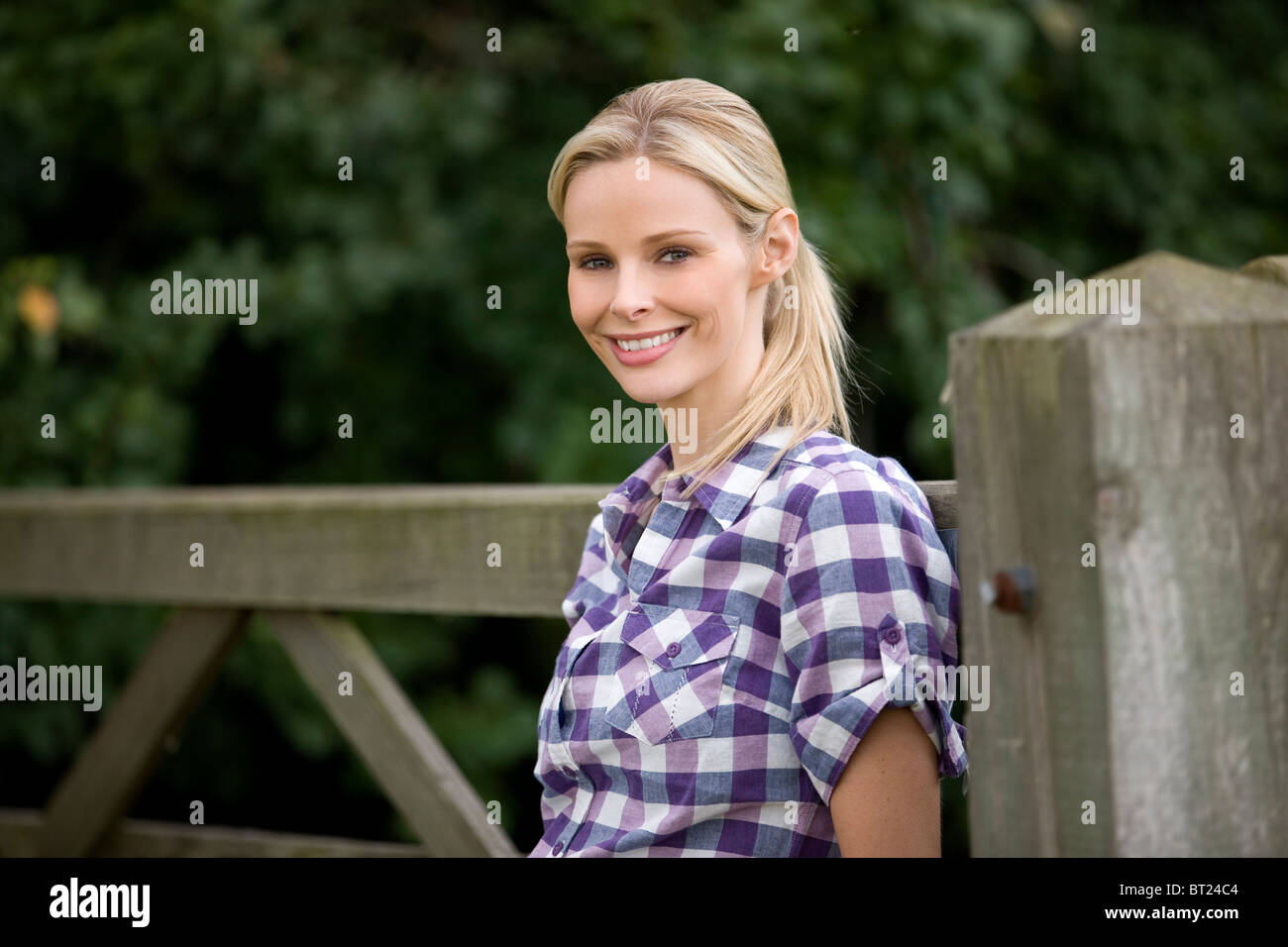 A portrait of a woman leaning on a country gate Stock Photo - Alamy