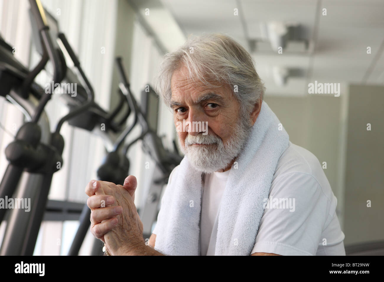 Physically fit and health conscious senior man in gym resting between ...