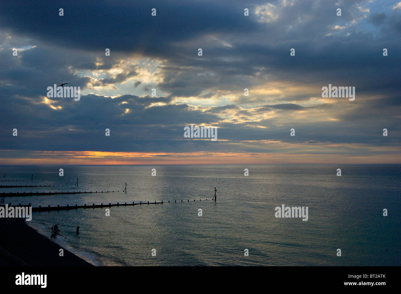 Dusk over a calm sea at Sheringham, Norfolk with silhouetted figures at ...