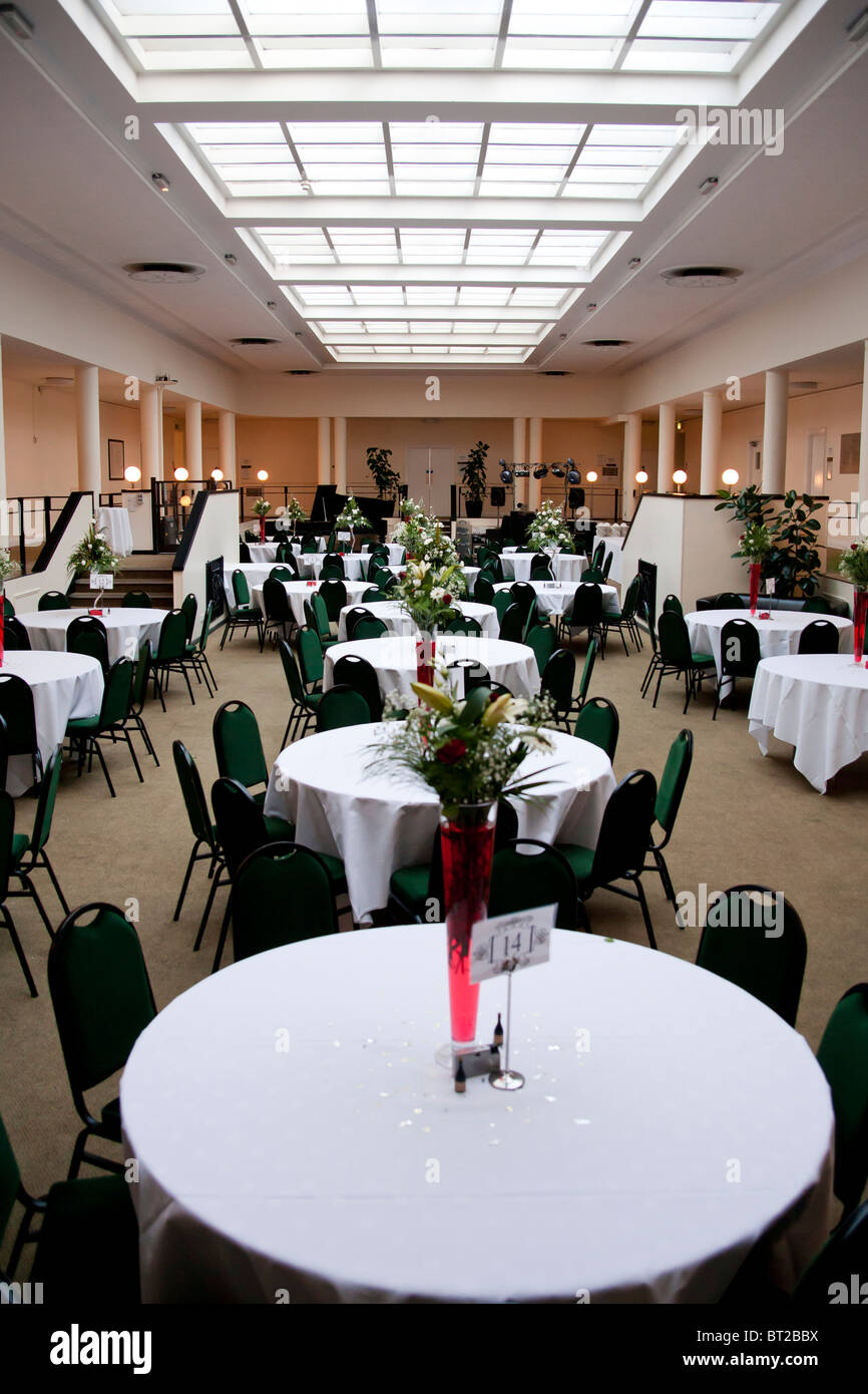 A glass-roofed hall set up for a wedding reception and party, with ...