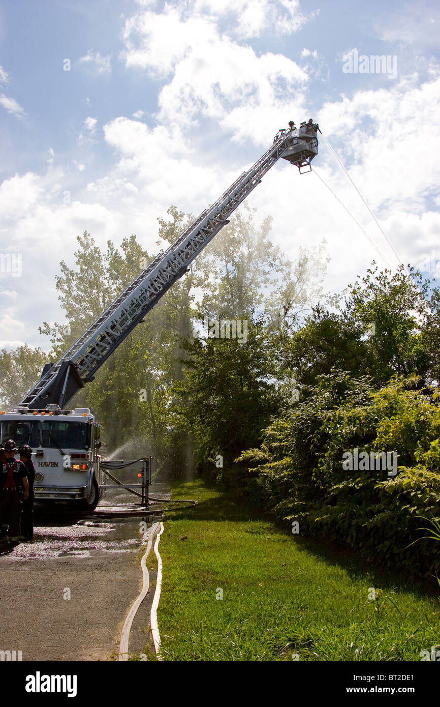 Firefighters training from ladder on ladder truck, with hoses, New ...