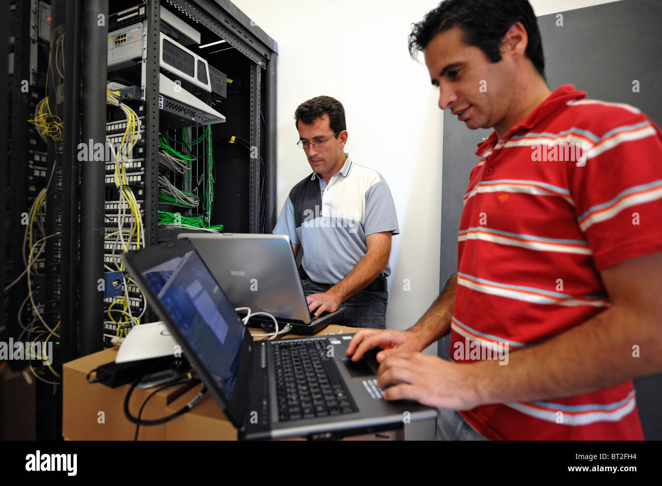 IT personnel on laptops fixing some problems with the main server Stock ...
