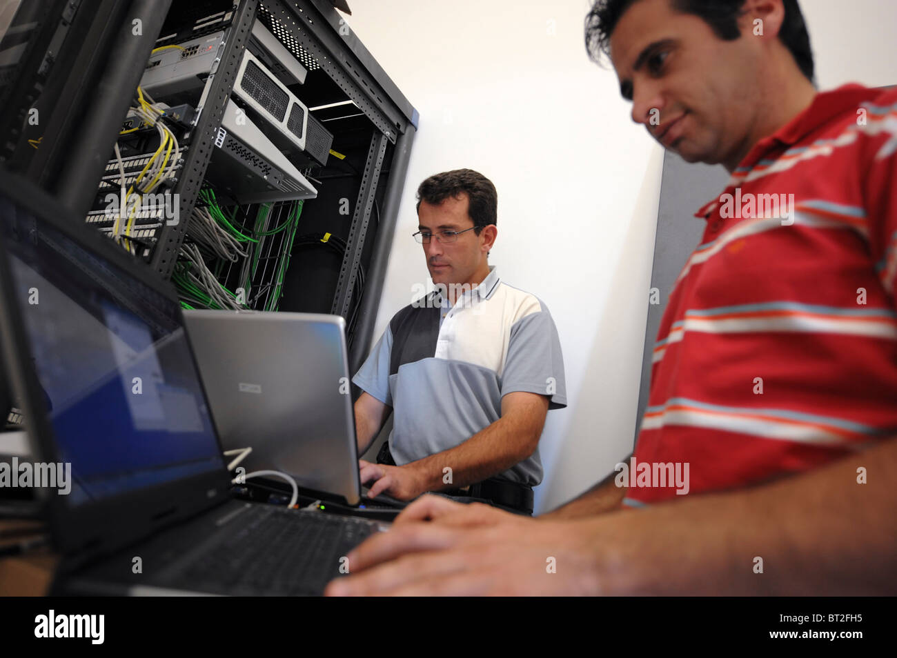 IT personnel on laptops fixing some problems with the main server Stock ...