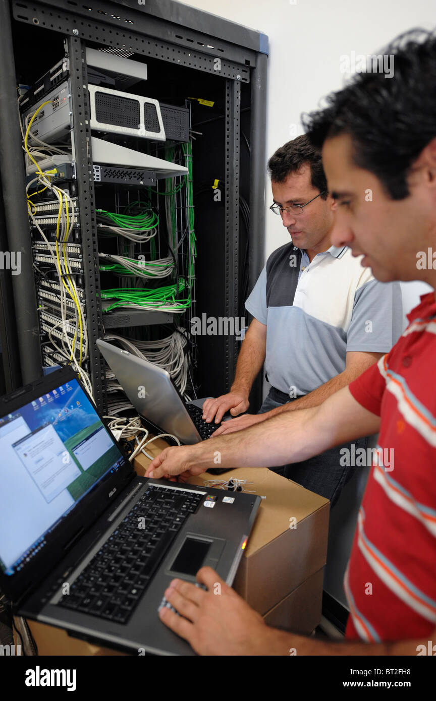 IT personnel on laptops fixing some problems with the main server Stock ...