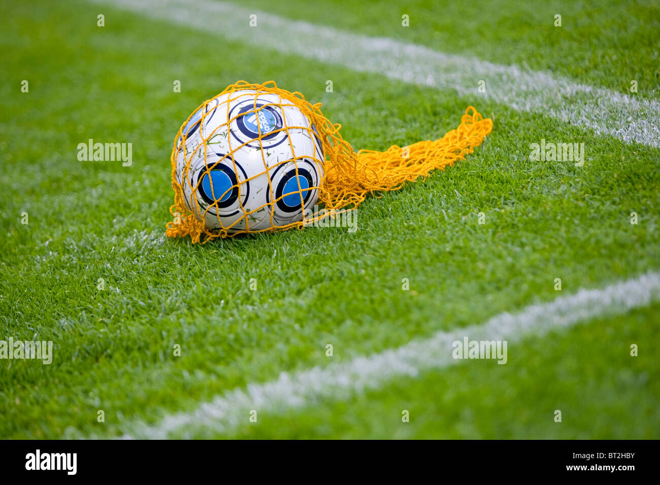 Soccer ball covered in net lying next to the side line on the field ...