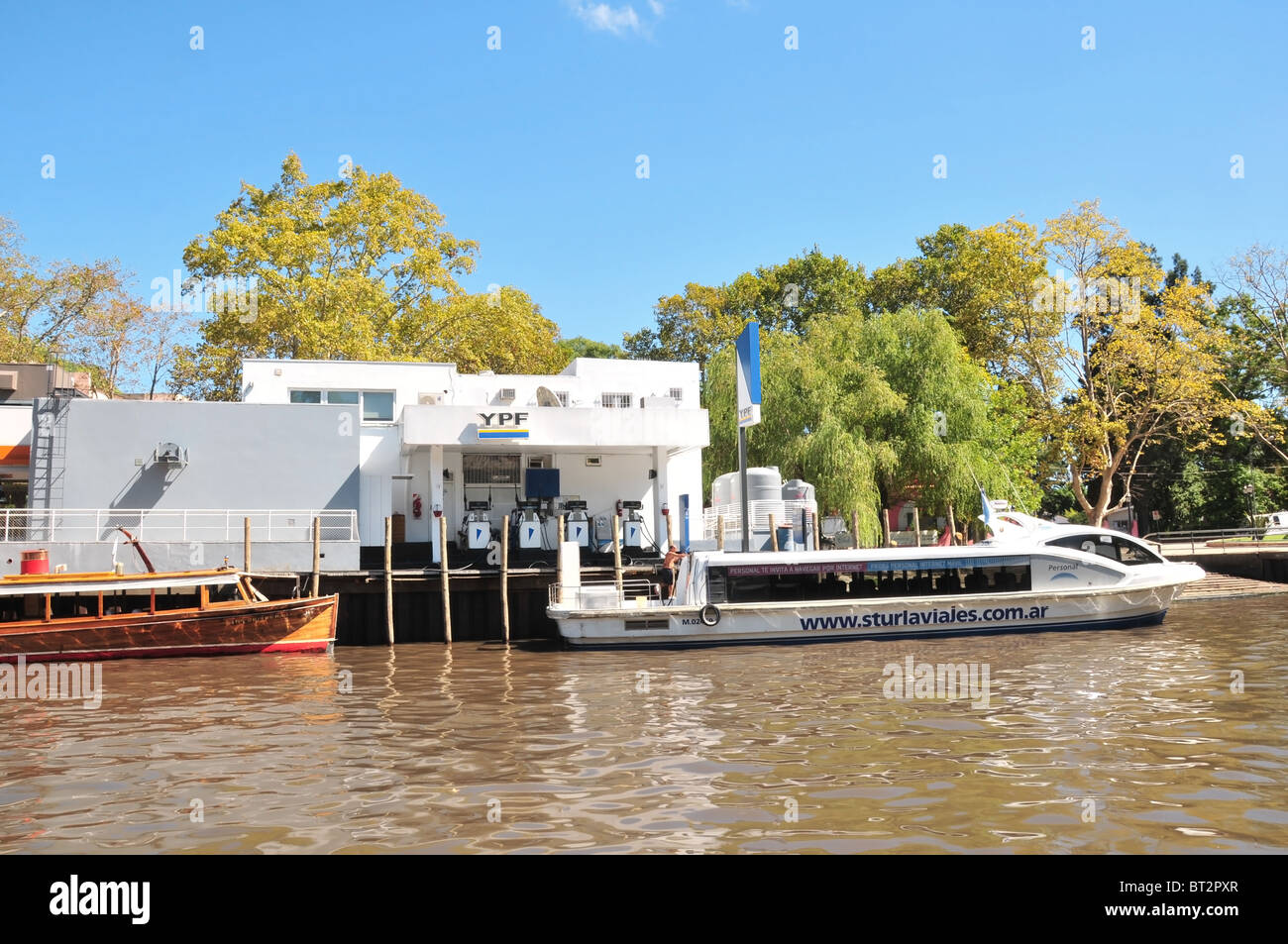 Man putting fuel into a tour barge, moored at a fuel filling station on ...