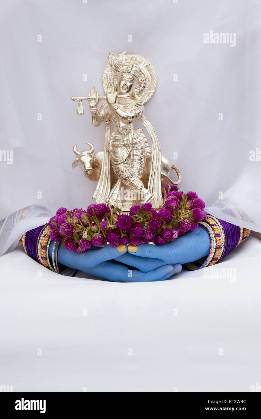 Indian girl holding a Silver Krishna statue with blue hands Stock Photo ...