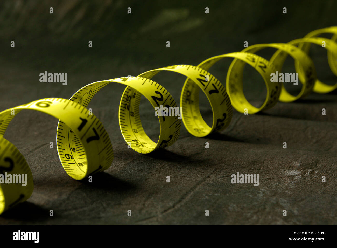 A coiled yellow tape measure against a dark background Stock Photo - Alamy