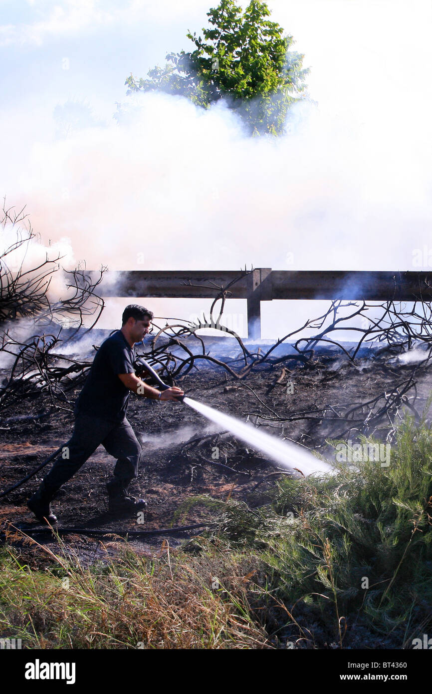 Fire fighter fighting the flames of a bush fire Stock Photo - Alamy