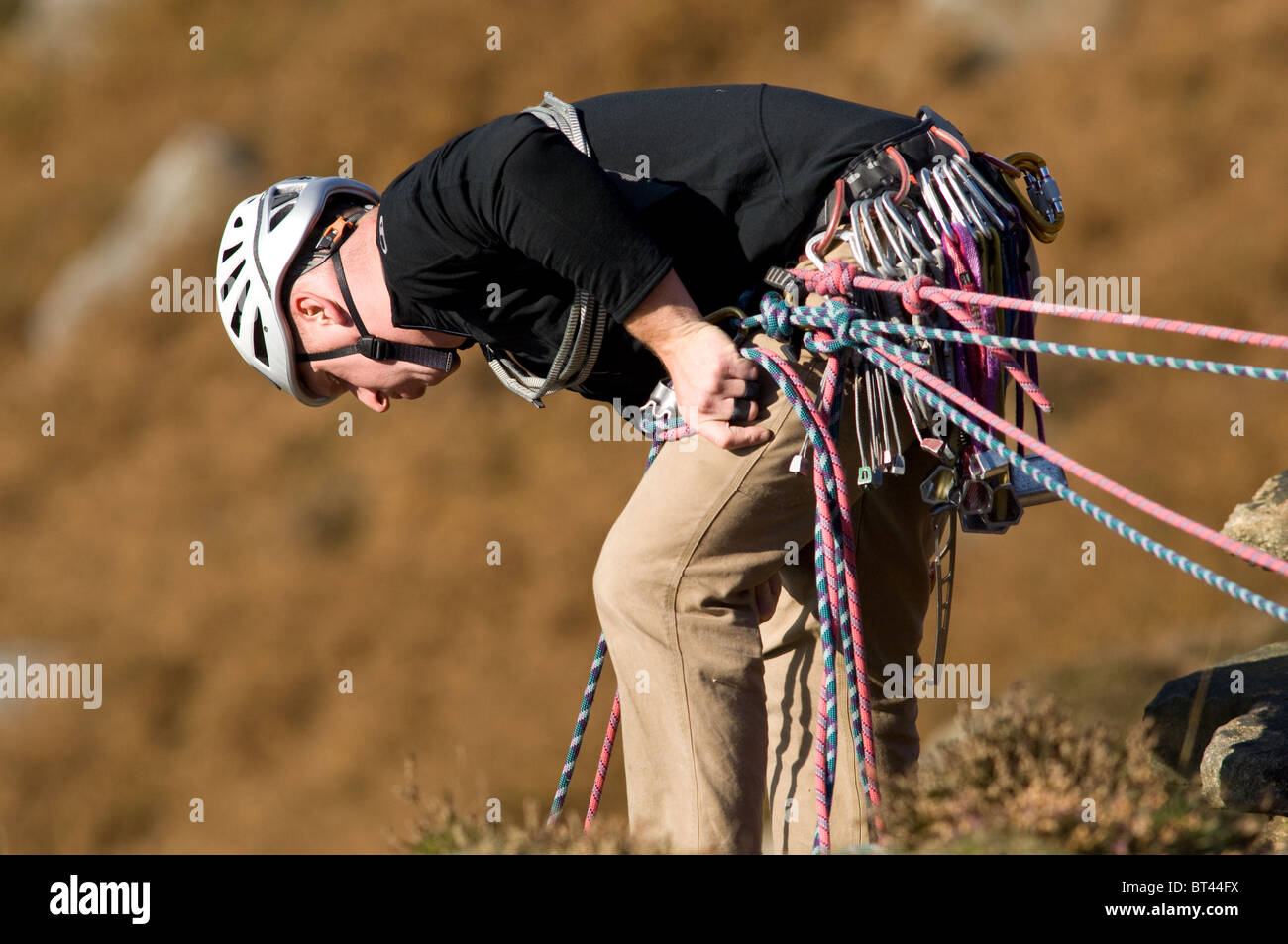 Rock climber helping to support fellow climber to scale a cliff face at ...