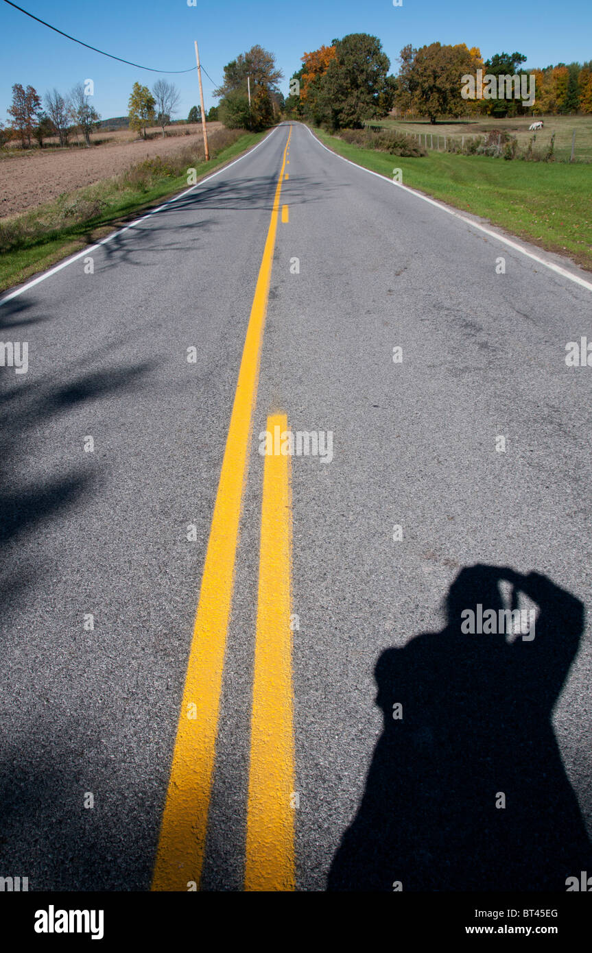 Photographers shadow on converging highway Stock Photo - Alamy