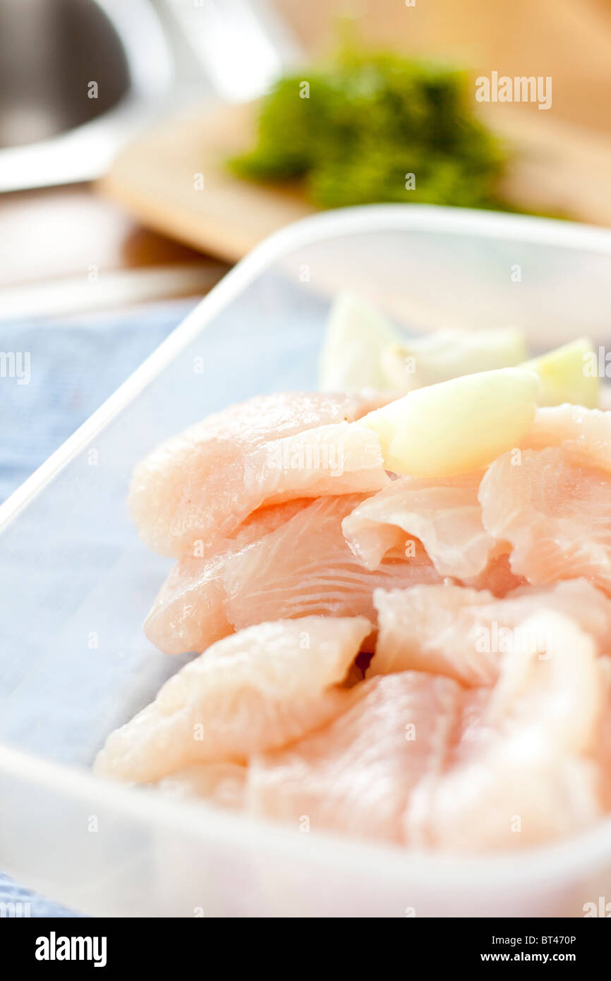 Slices of raw fish fillet in a glass bowl, prepared for cooking or ...