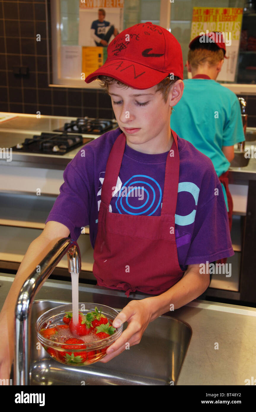 schoolboy washing fruit in cooking class Stock Photo - Alamy