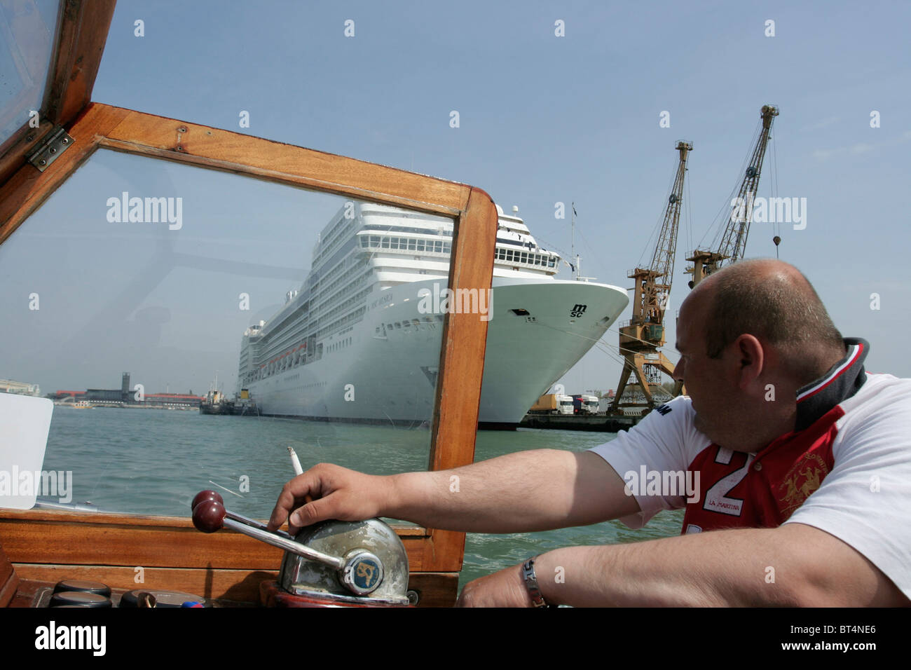 A boat operator passing by an ocean liner in Venice, Italy Stock Photo ...
