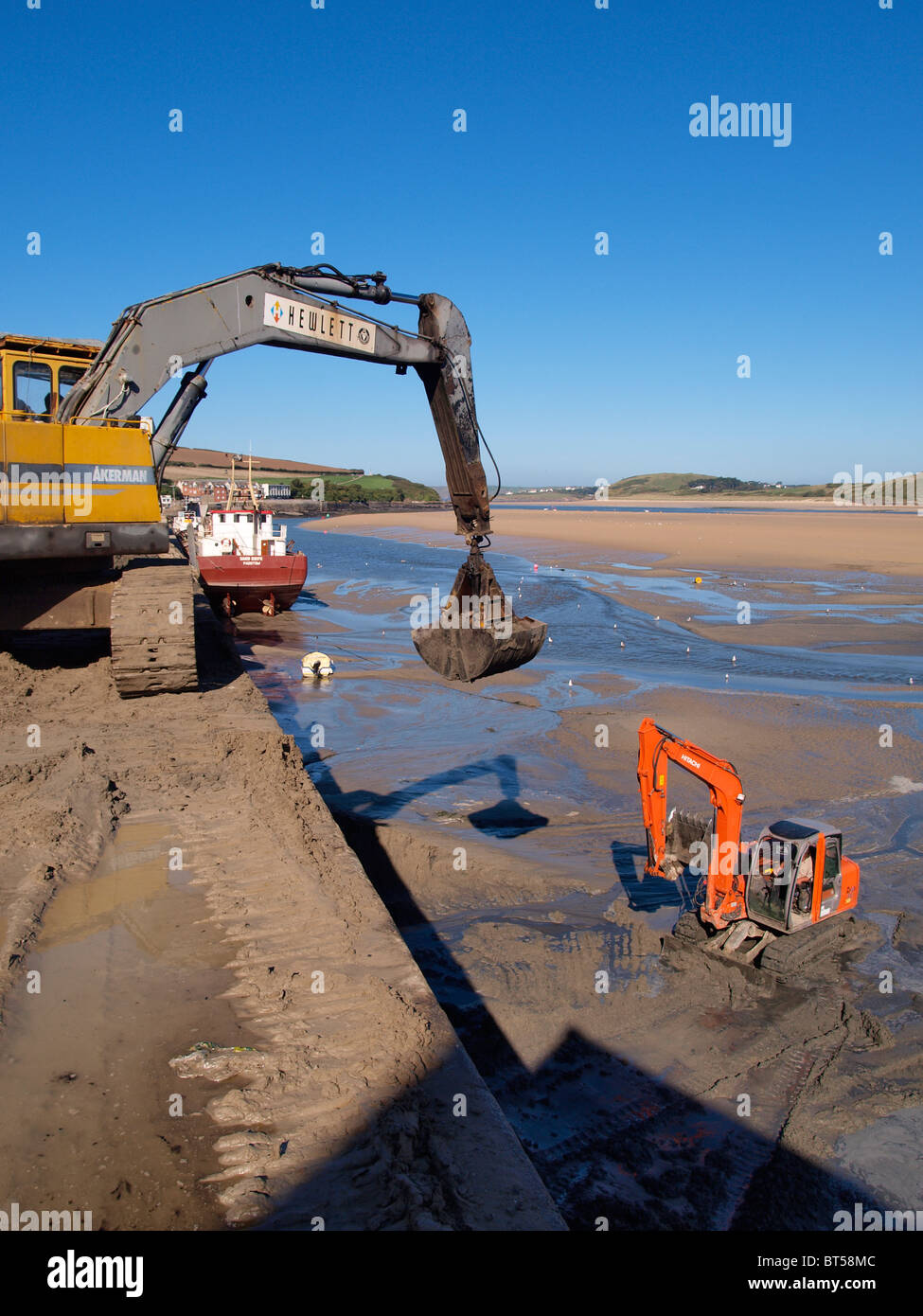 Diggers digging sand from Padstow harbour at low tide, Cornwall, UK ...