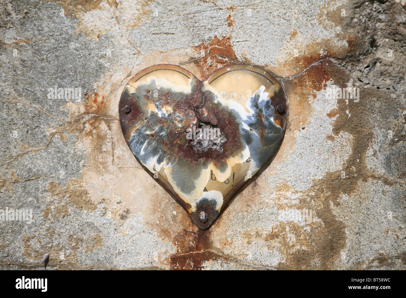 An old heart ornament on a stone wall at a French gravesite, close up ...