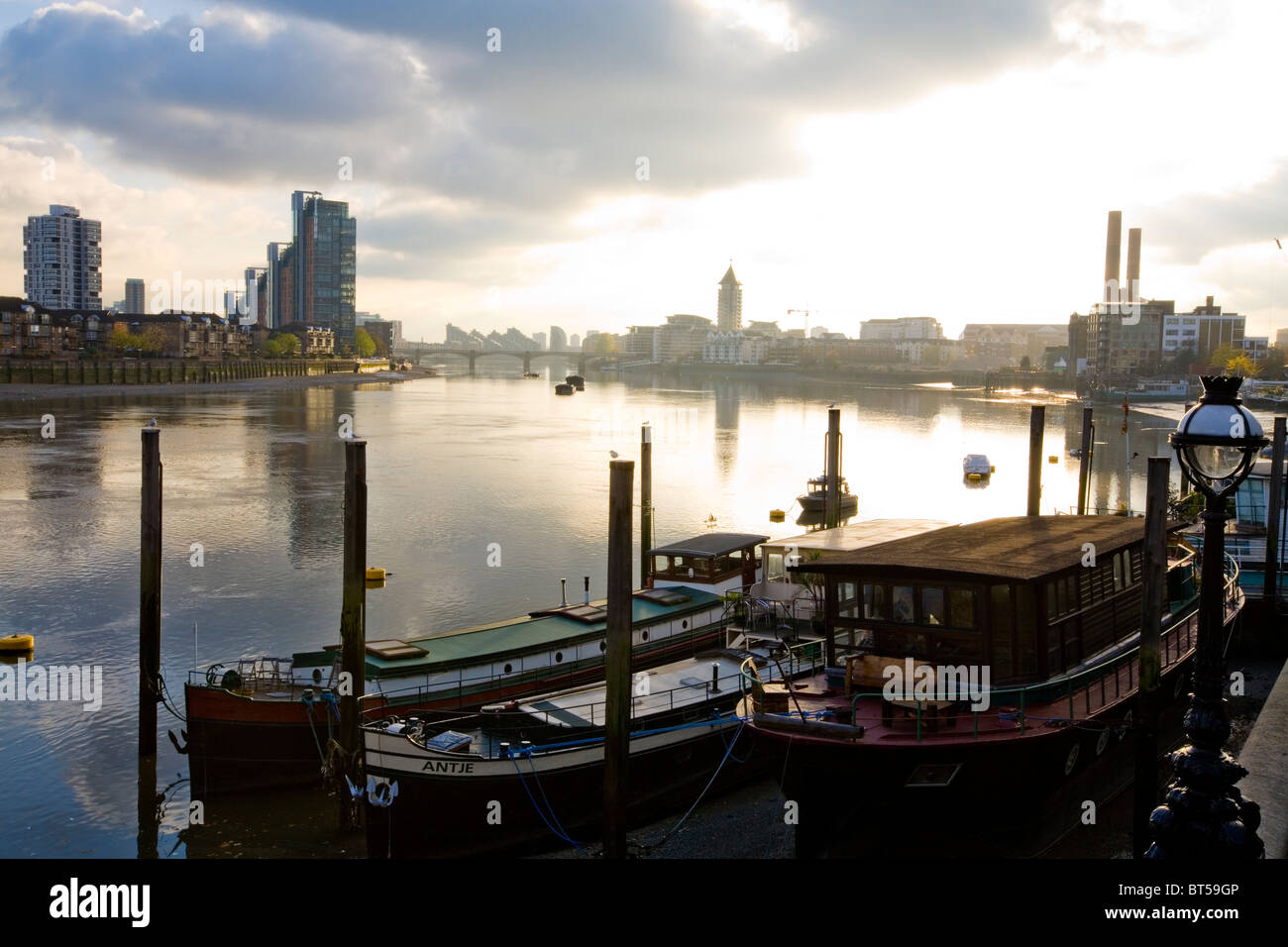 A river scene on the Thames at Chelsea in London with moored barges in ...
