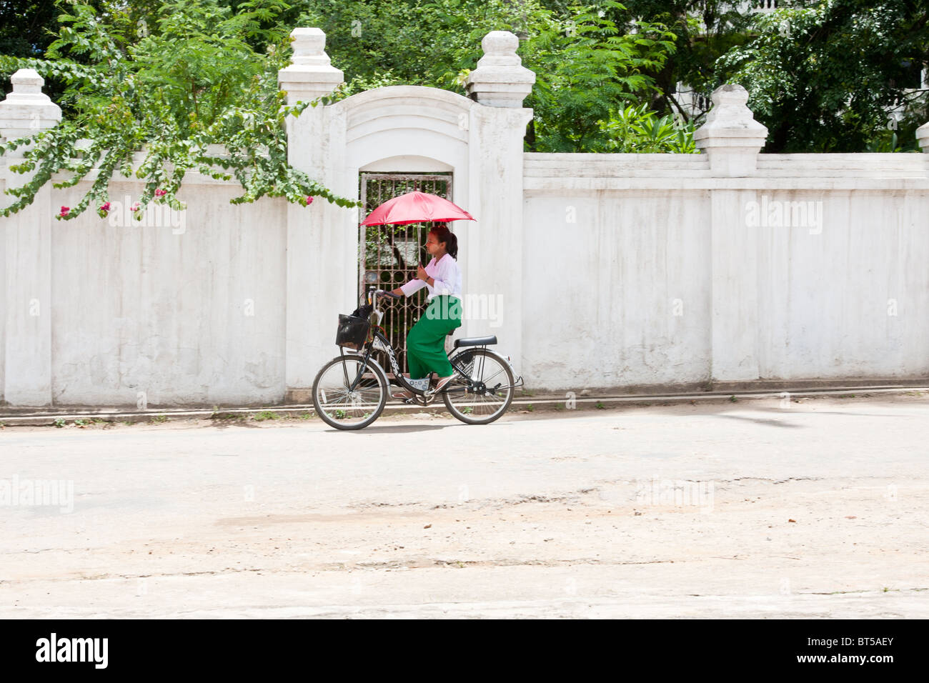 A Burmese student rides her bike past a white wall in Chiang tong ...