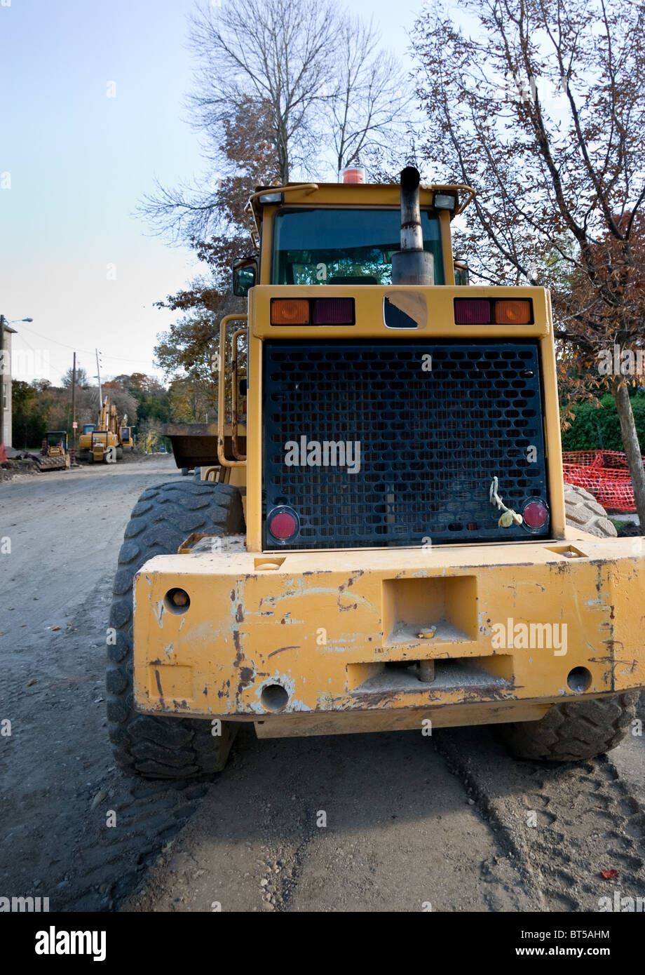 A closeup of the front of a yellow tractor with the roadway under ...