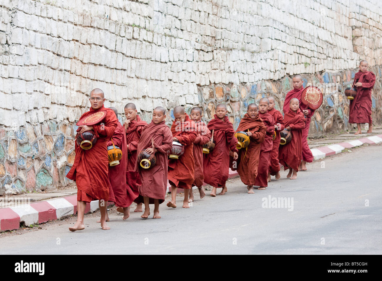 A monk is followed by novice monks during their daily alms ceremony ...