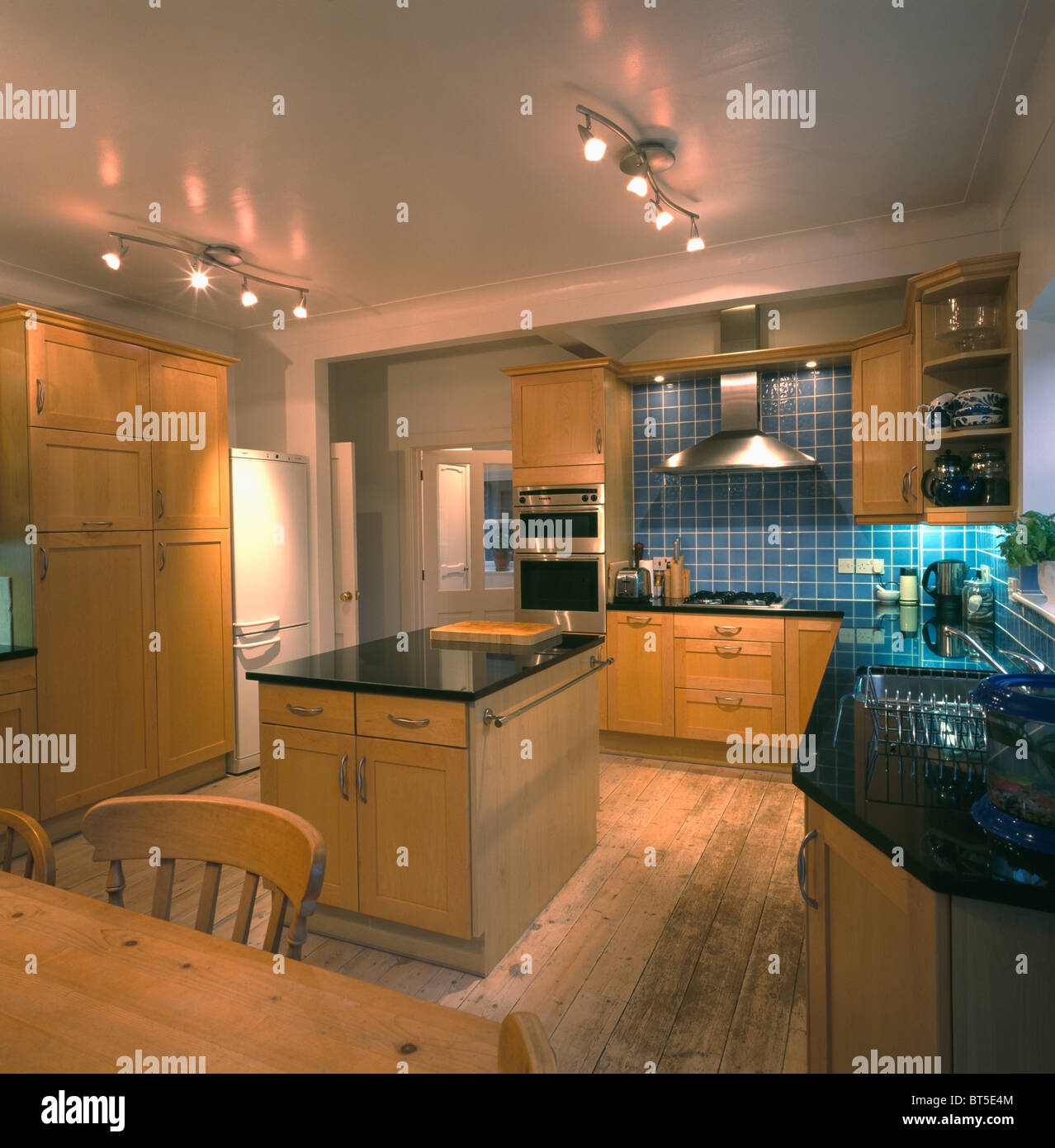Track lighting in modern kitchen with granite-topped island unit and ...