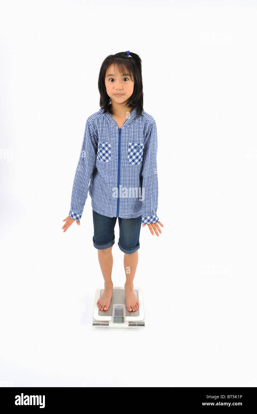 Girl standing on weight scale Stock Photo - Alamy
