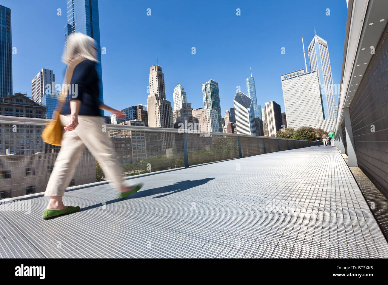 A pedestrian walks the Nichols Bridgeway with the Skyline of Chicago ...