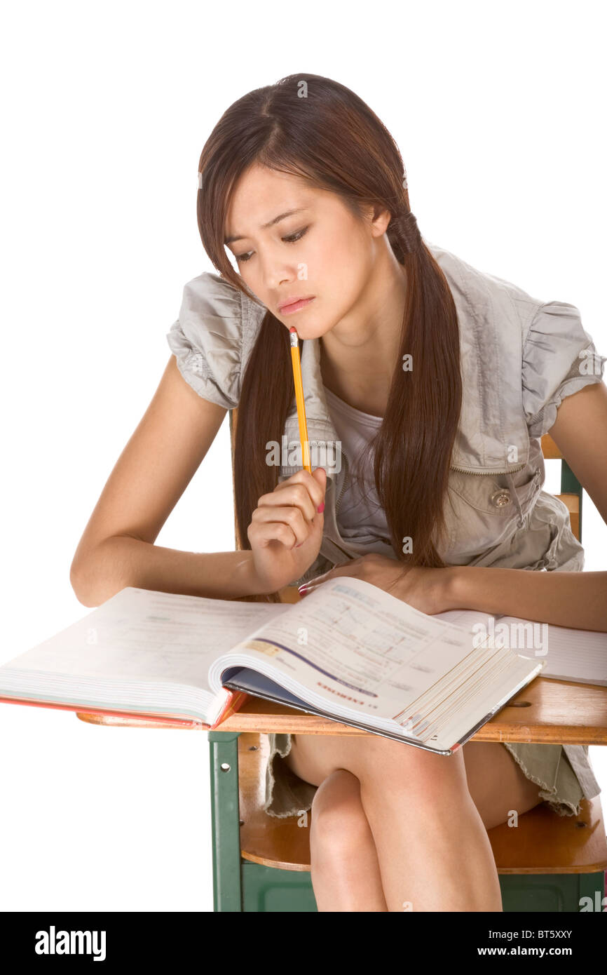 Asian student girl sitting by the desk and studying huge math book ...