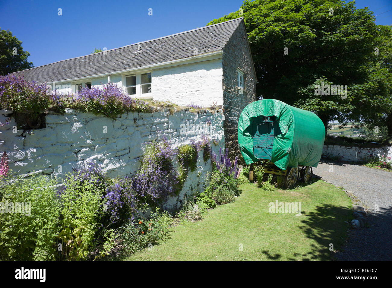 a gypsy caravan covered in tarpaulin outside a country cottage in ...