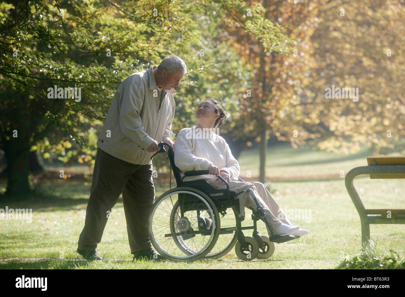 old man pushing woman on wheelchair Stock Photo - Alamy