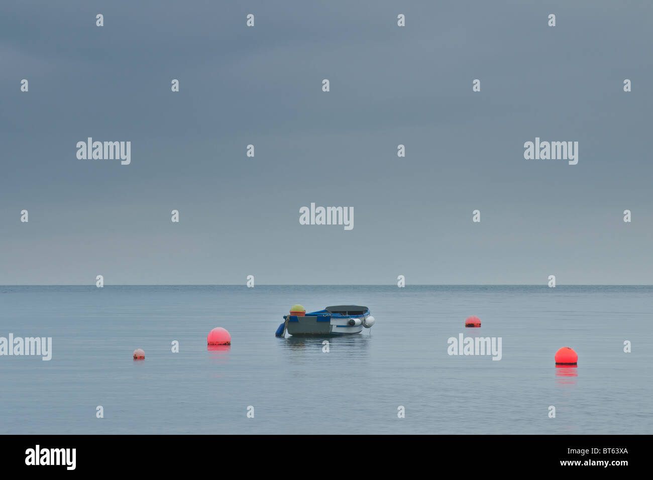 Lone boat in a triangle of buoys on a calm sea Stock Photo - Alamy