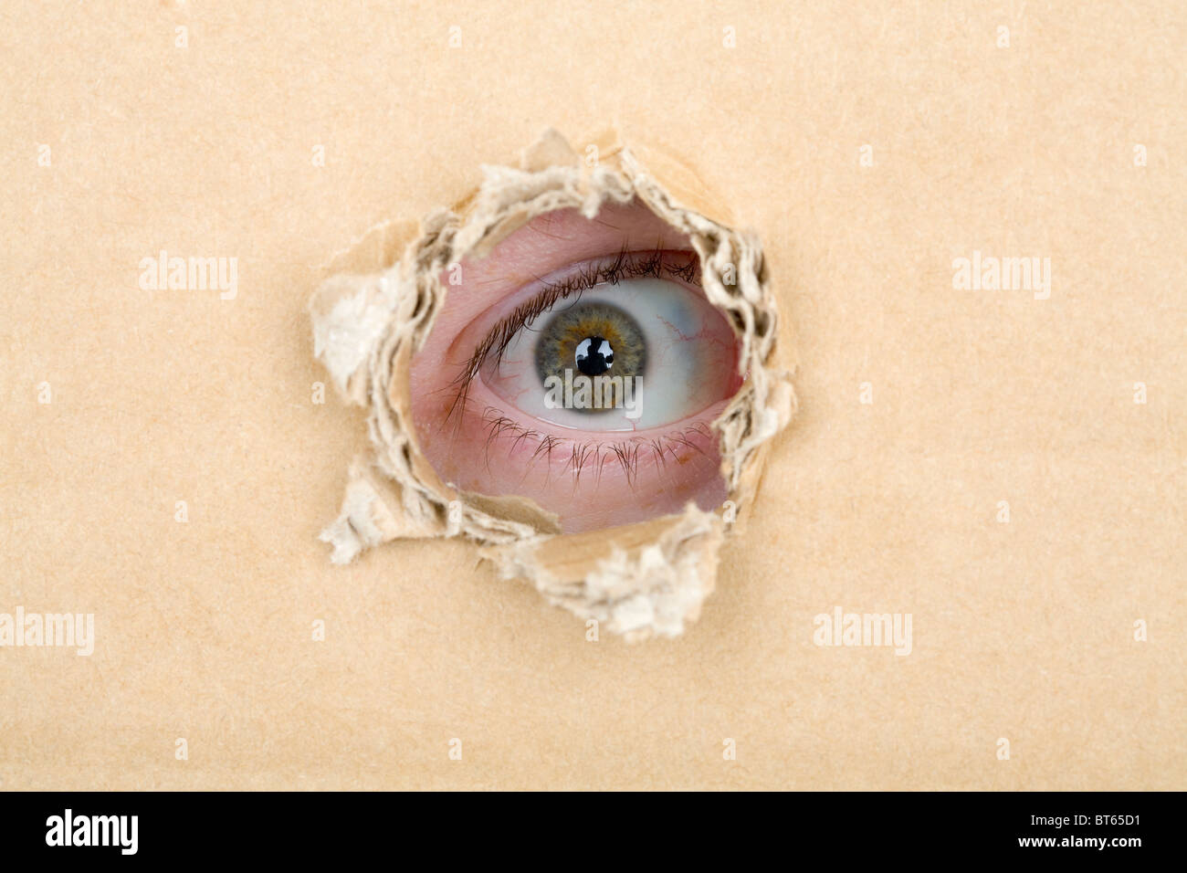 Eye looking from a hole in a sheet of cardboard Stock Photo - Alamy